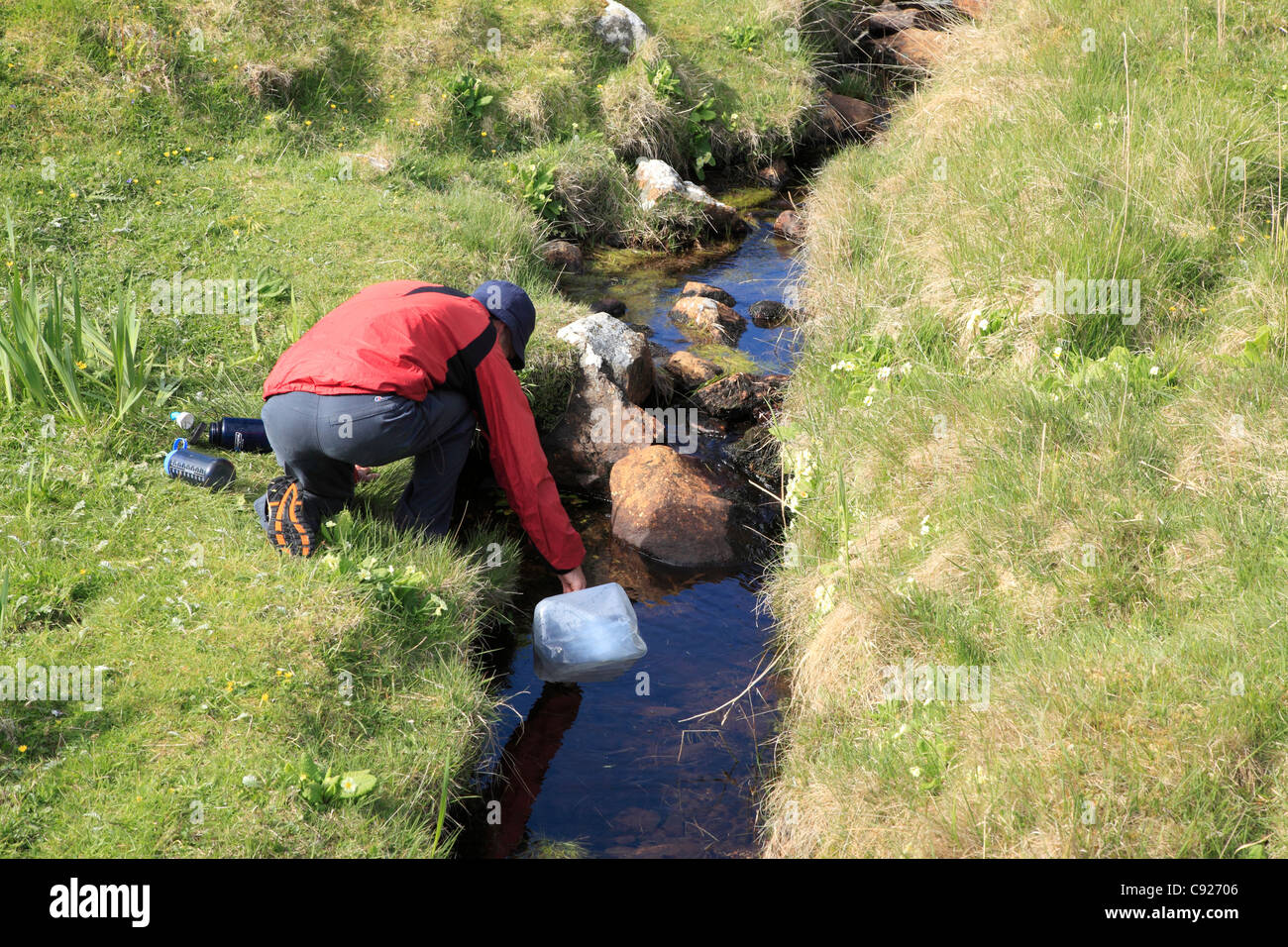 A person collecting drinking water from a stream on the island of ...