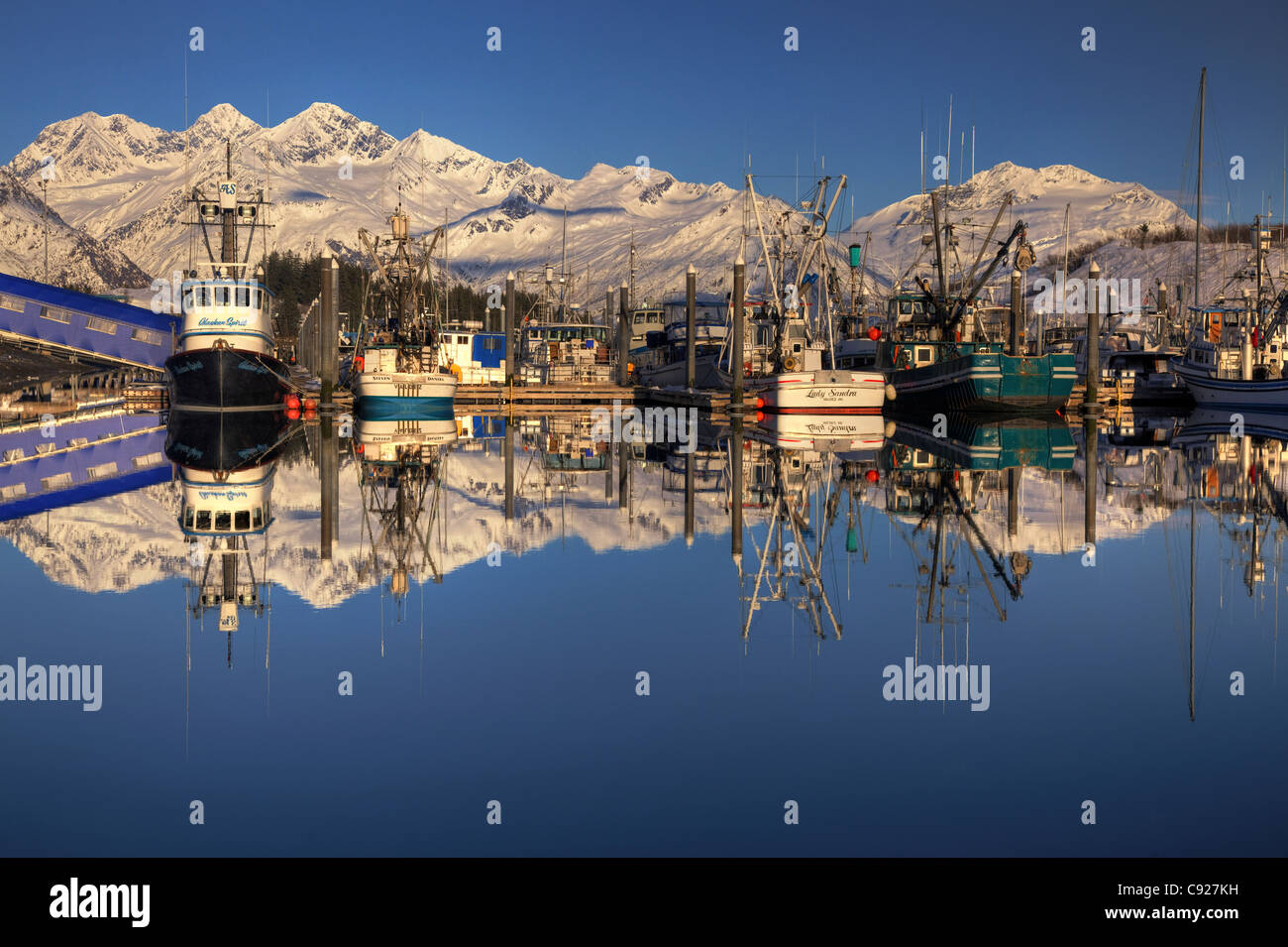 Valdez Harbor with boats and mountains reflected in the water in the ...