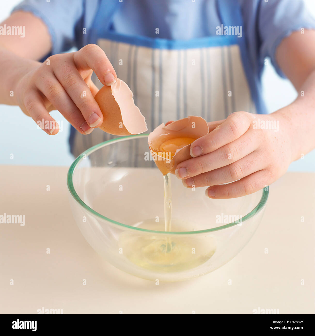 Breaking egg over glass bowl, separating eggs Stock Photo - Alamy