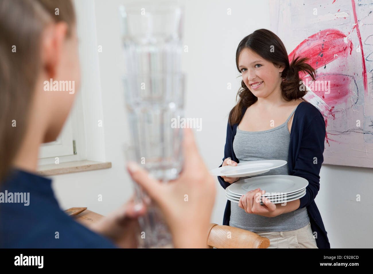 Girls putting away dishes in kitchen Stock Photo - Alamy