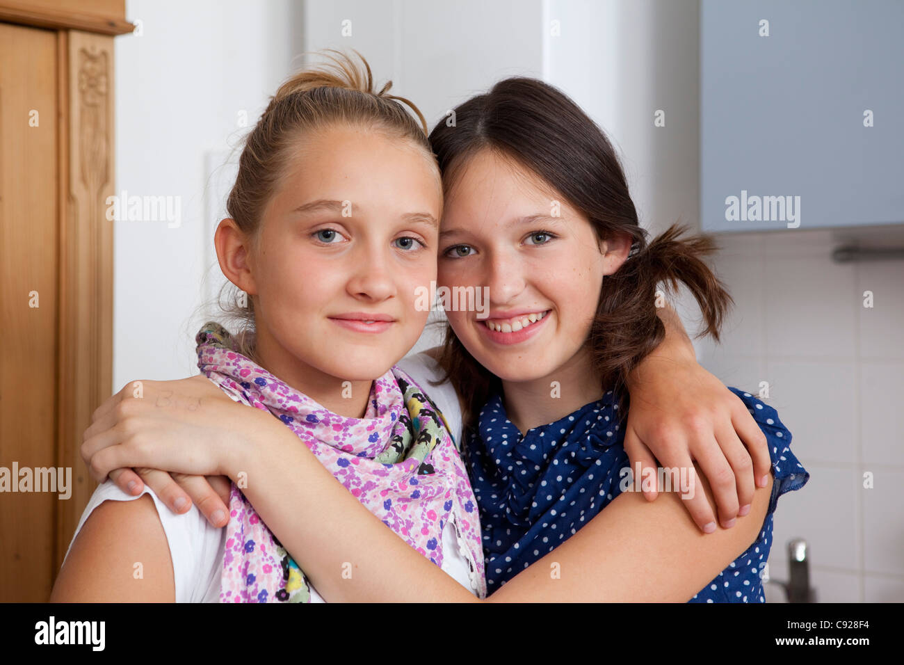 Smiling girls hugging in kitchen Stock Photo - Alamy