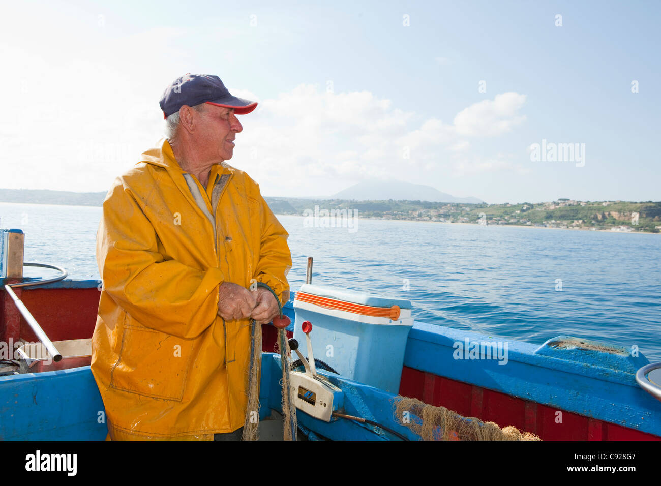 Fisherman reeling in nets on boat Stock Photo - Alamy