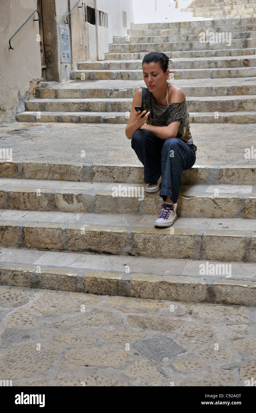 Young woman sitting on stairs outdoors text messaging Stock Photo - Alamy