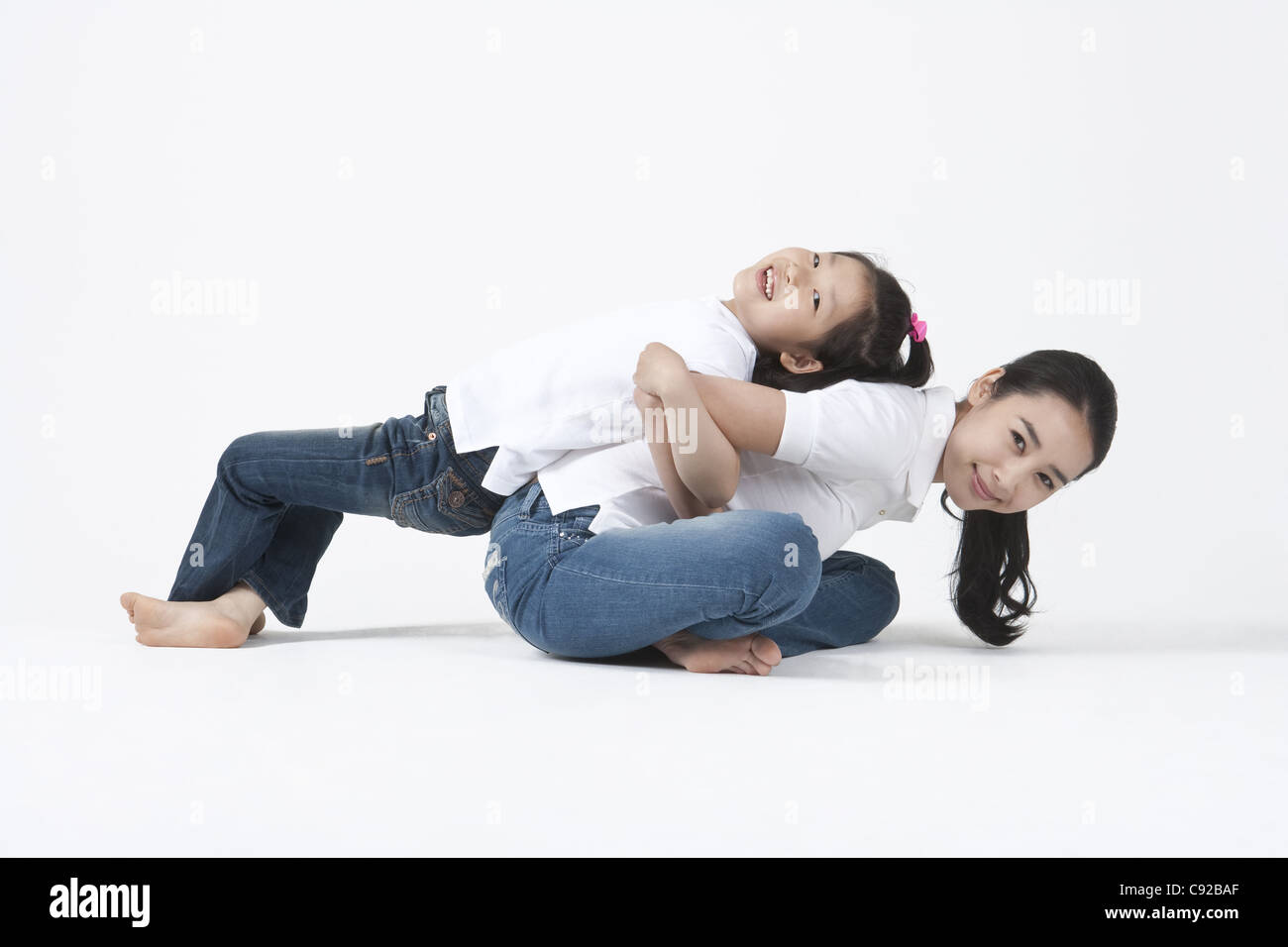 Mother and daughter exercising with linking arms back to back, smiling ...