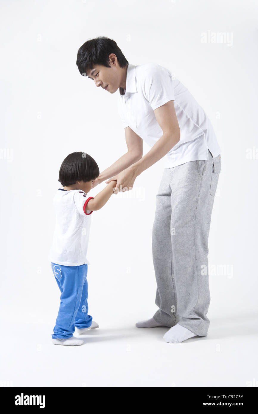 Studio shot of man helping boy to walk Stock Photo - Alamy
