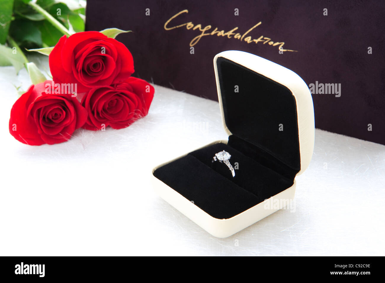 Diamond ring in box with red rose and congratulation note Stock Photo ...