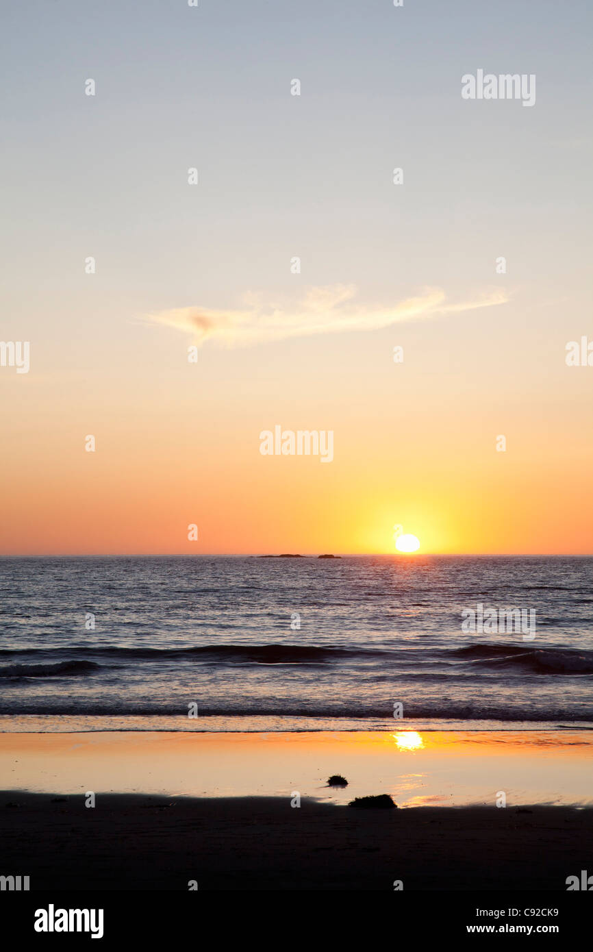 Sun setting over ocean on beach Stock Photo - Alamy