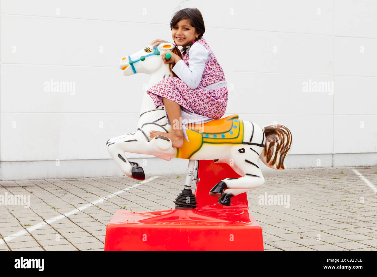 Girl riding mechanical horse outdoors Stock Photo - Alamy