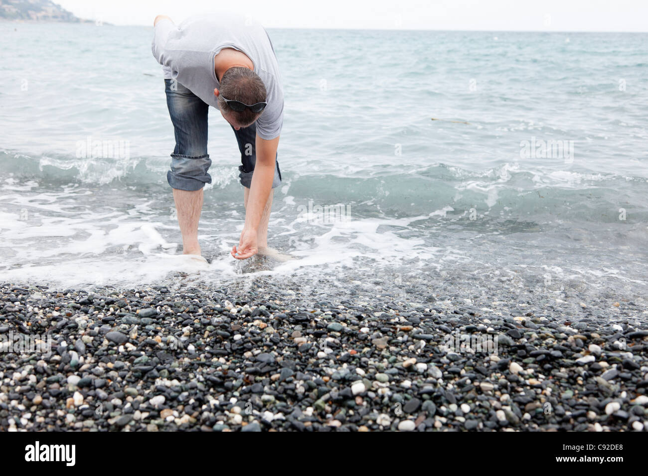 Man collecting pebbles on rocky beach Stock Photo - Alamy