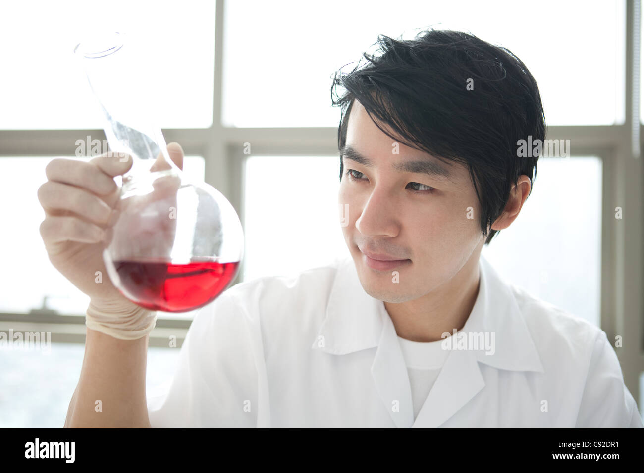 Scientist holding glass beaker Stock Photo - Alamy