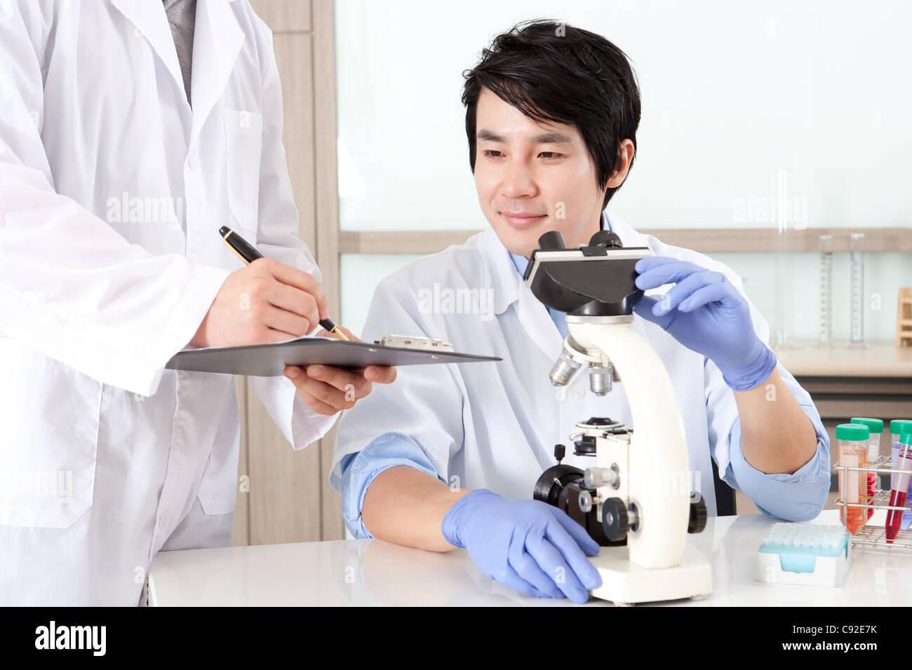 Man talking with his colleague scientist in lab sitting in front of ...