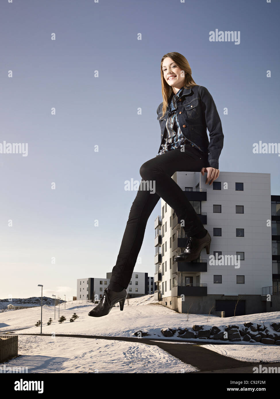 Oversized woman sitting on building Stock Photo - Alamy