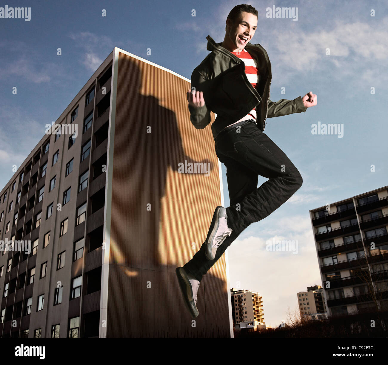 Oversized man jumping by building Stock Photo - Alamy