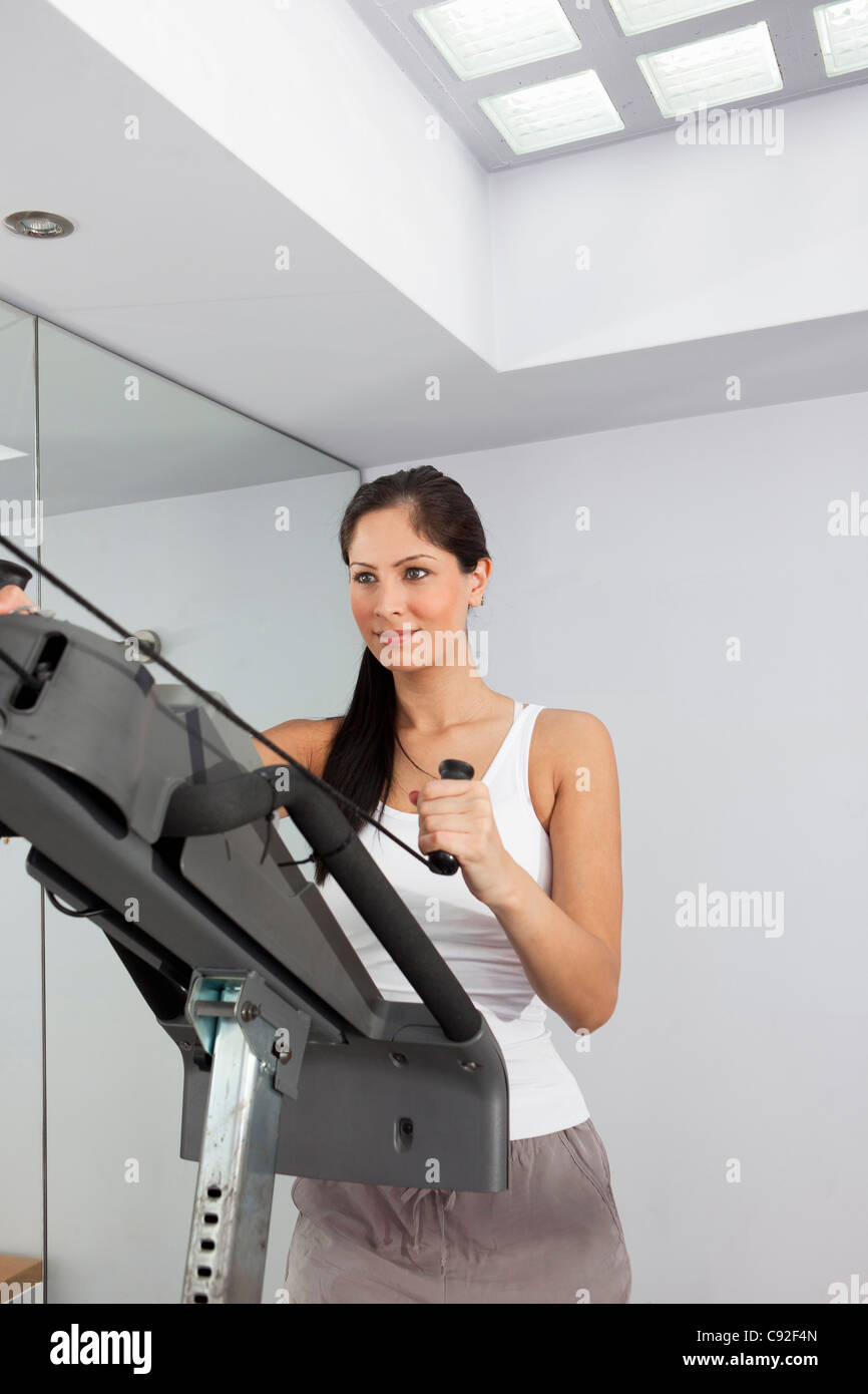 Smiling woman using exercise machine Stock Photo - Alamy