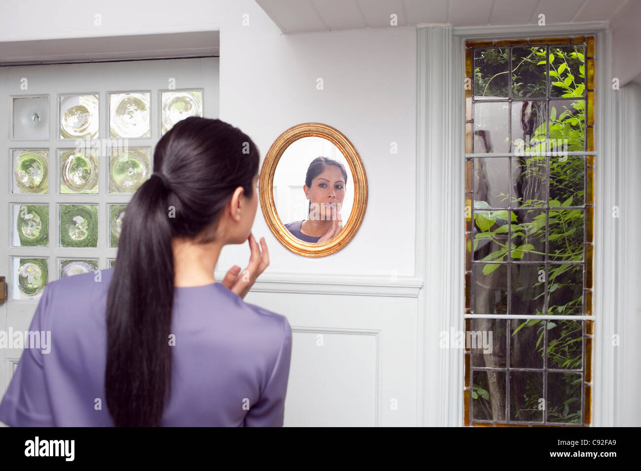 Woman examining her makeup in mirror Stock Photo - Alamy