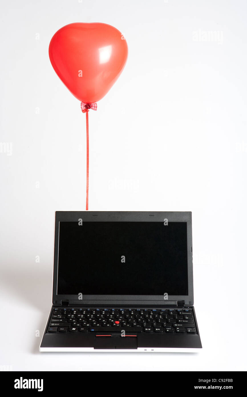 Laptop with heart shape balloon on white background Stock Photo - Alamy