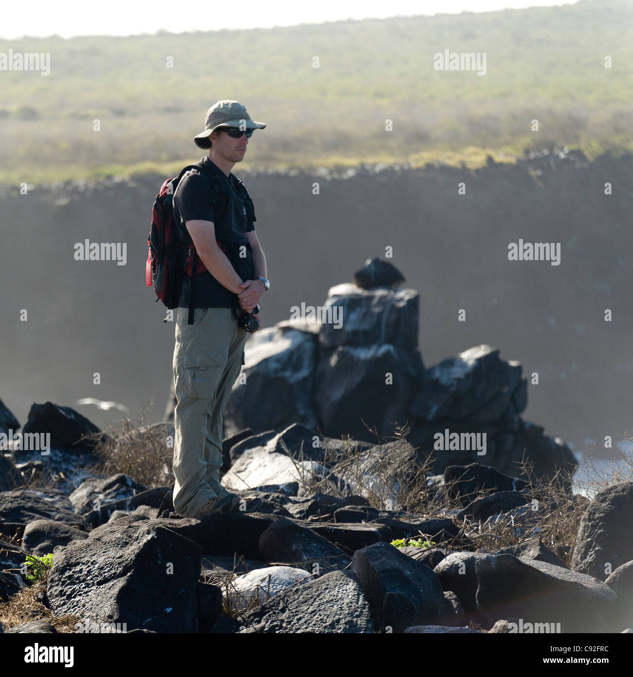 Tourist standing at a rocky coast, Punta Suarez, Espanola Island ...