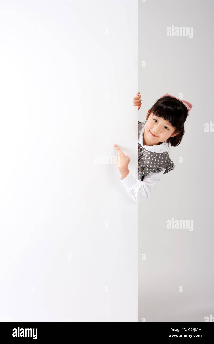 Girl peeking around wall, looking at camera Stock Photo - Alamy