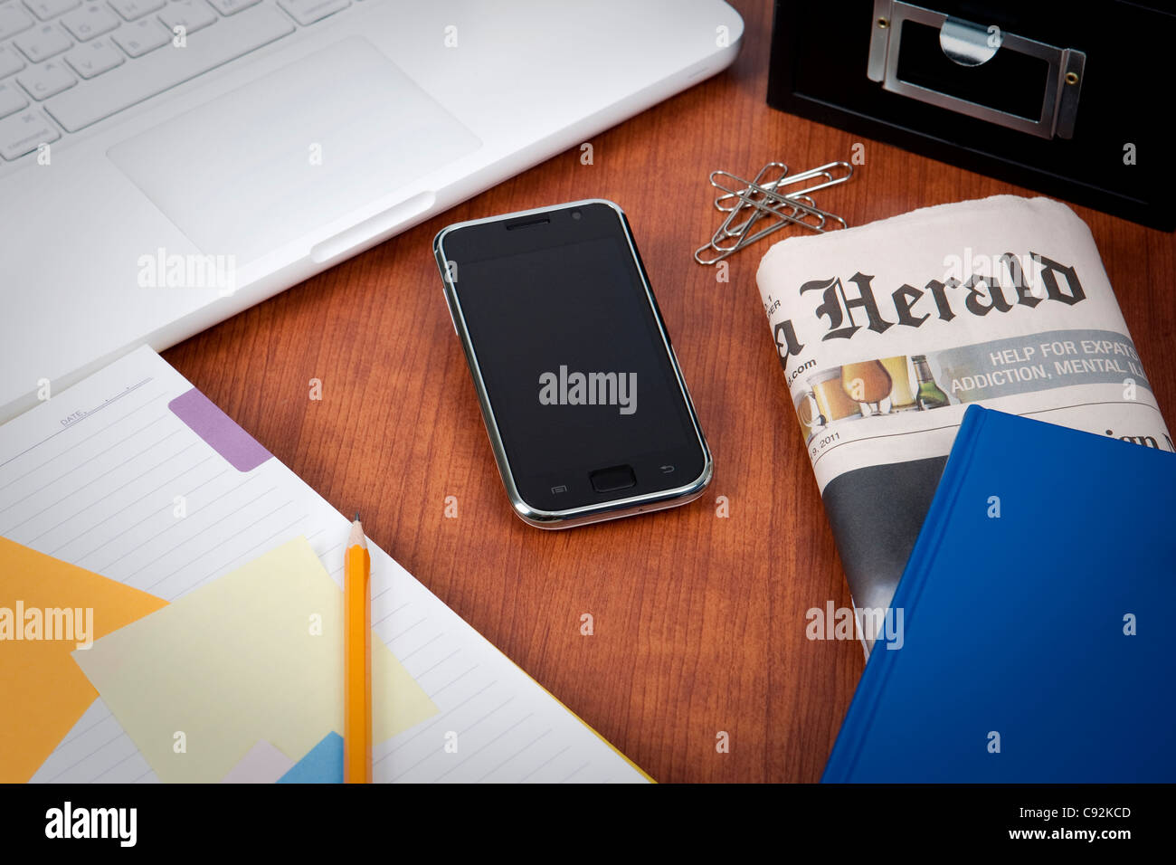Laptop and mobile phone with notepad and newspaper Stock Photo - Alamy