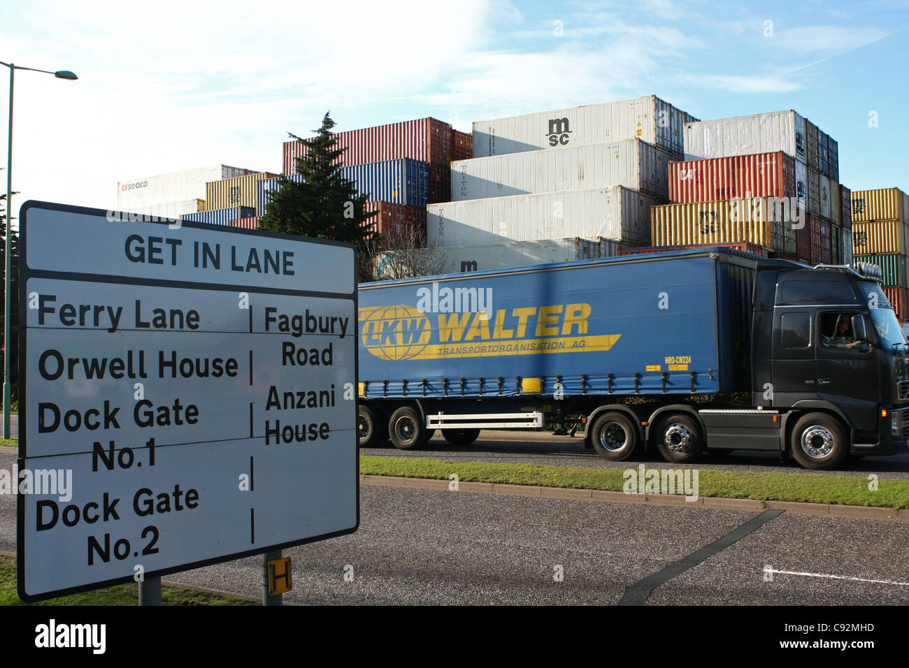 container truck passing stacked containers and a road sign showing ...