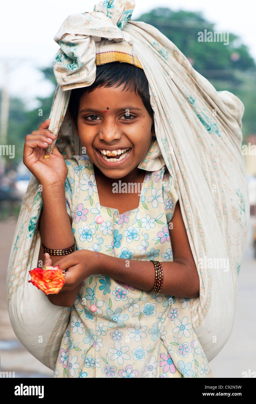 Smiling happy Indian village girl carry the laundry on her head. Andhra ...