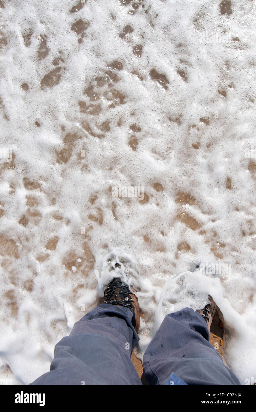 Tide washing over walking boots Stock Photo - Alamy
