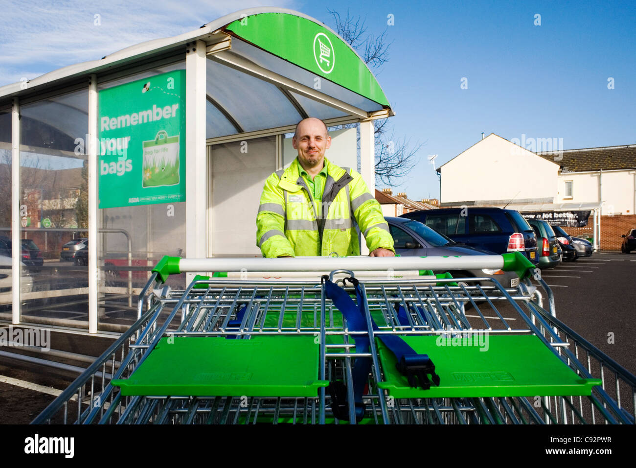 man working at a supermarket pushing shopping trolleys Stock Photo - Alamy
