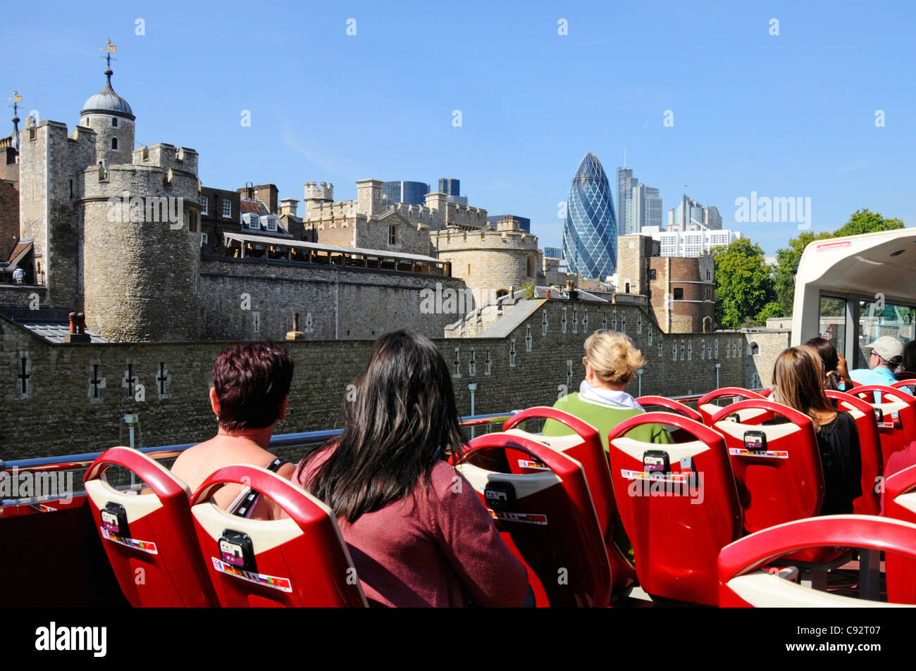 Tourists on top deck of open top bus with views of Tower of London ...