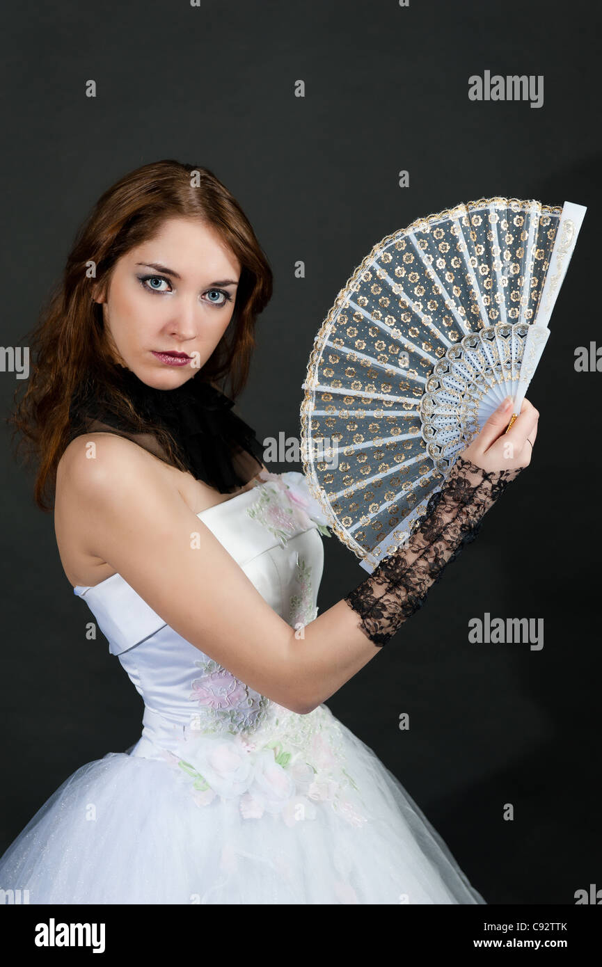 Girl with fan in white dress on black background Stock Photo - Alamy