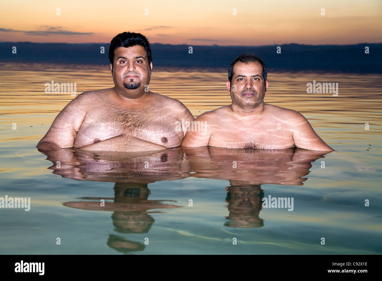Two Jordanian men / male / man tourist / tourists relax the high salt ...