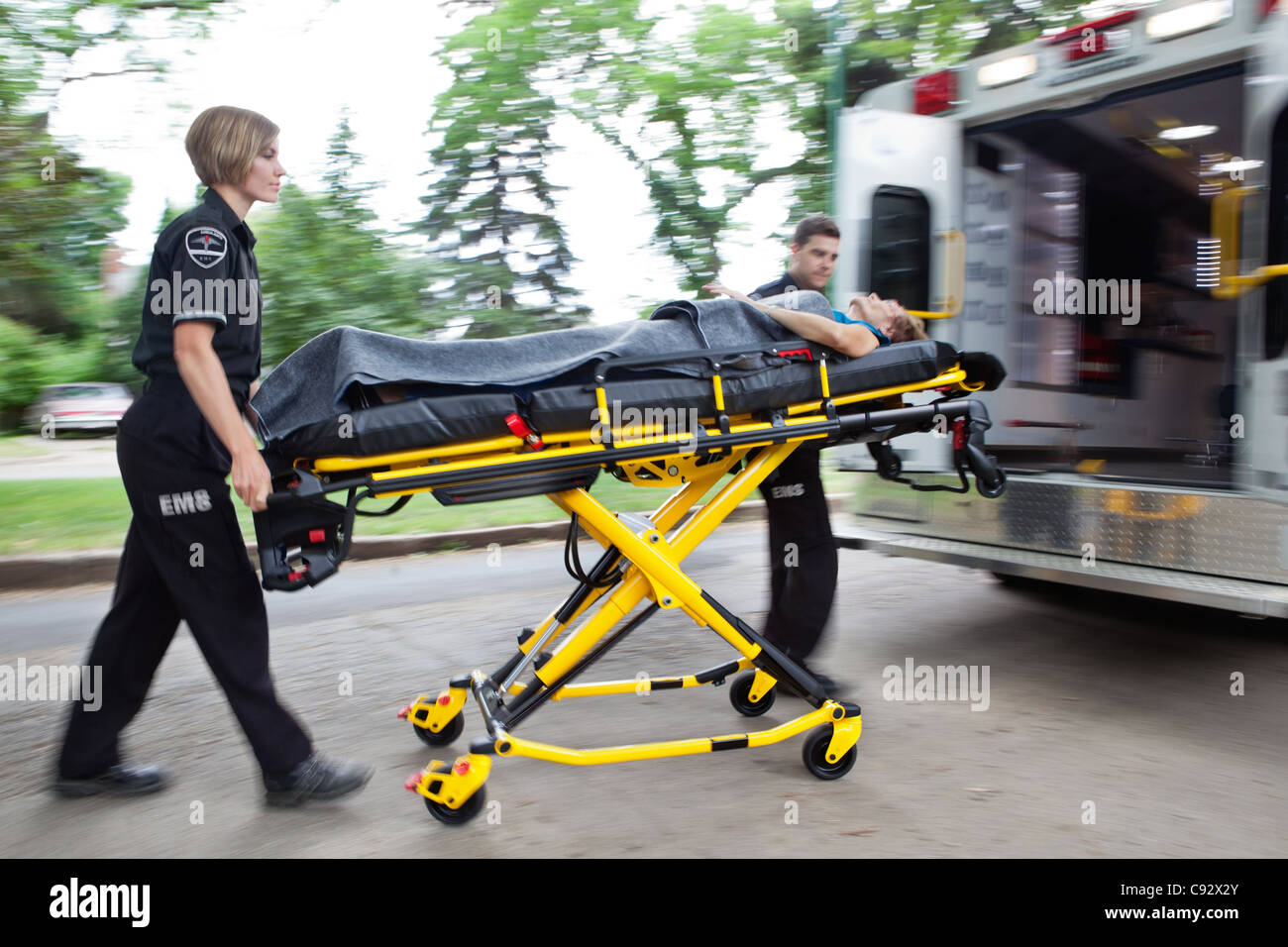 Man and woman ambulance team rushing a senior woman into the vehicle ...