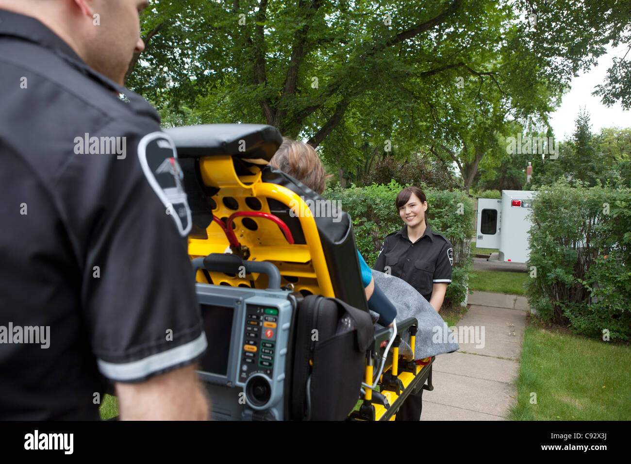 Two ambulance workers pushing elderly patient to vehicle Stock Photo ...