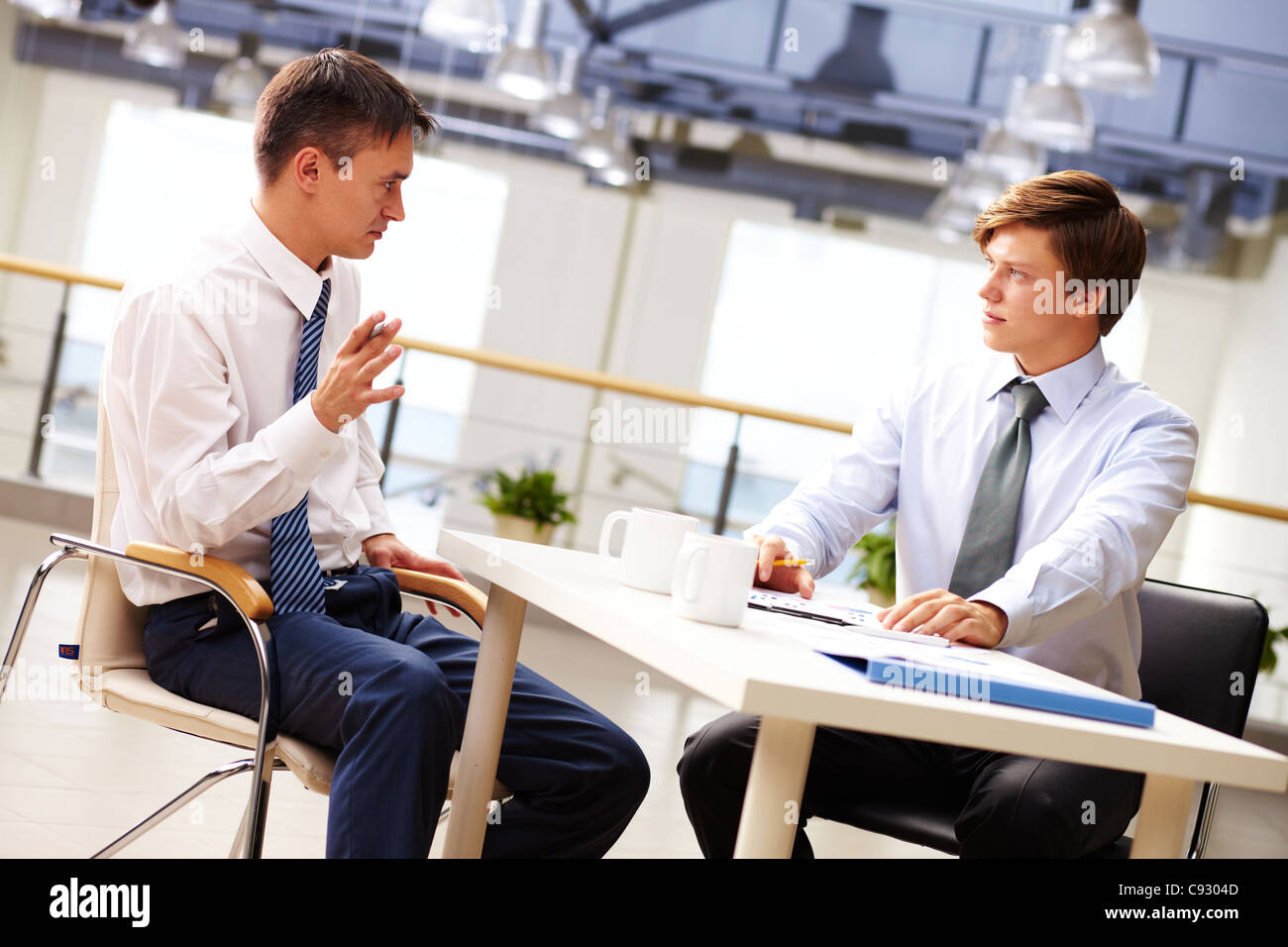 Two businessmen sitting at table and discussing strategy Stock Photo ...