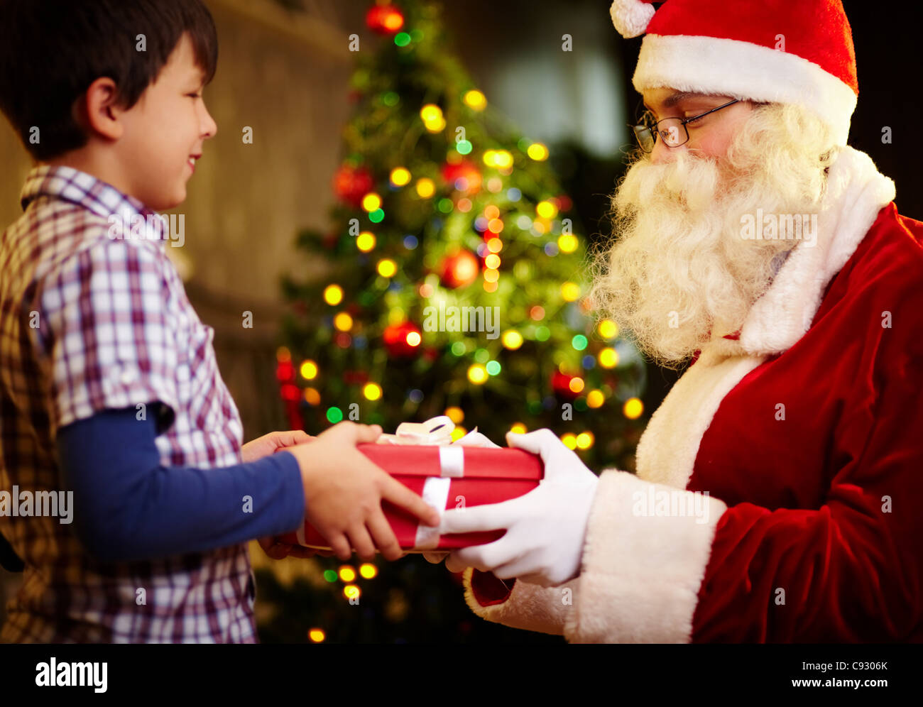 Photo of happy boy taking gift from Santa Claus hands Stock Photo - Alamy