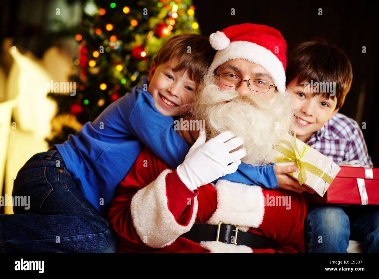 Photo of happy boy embracing Santa Claus with cute kid near by Stock ...