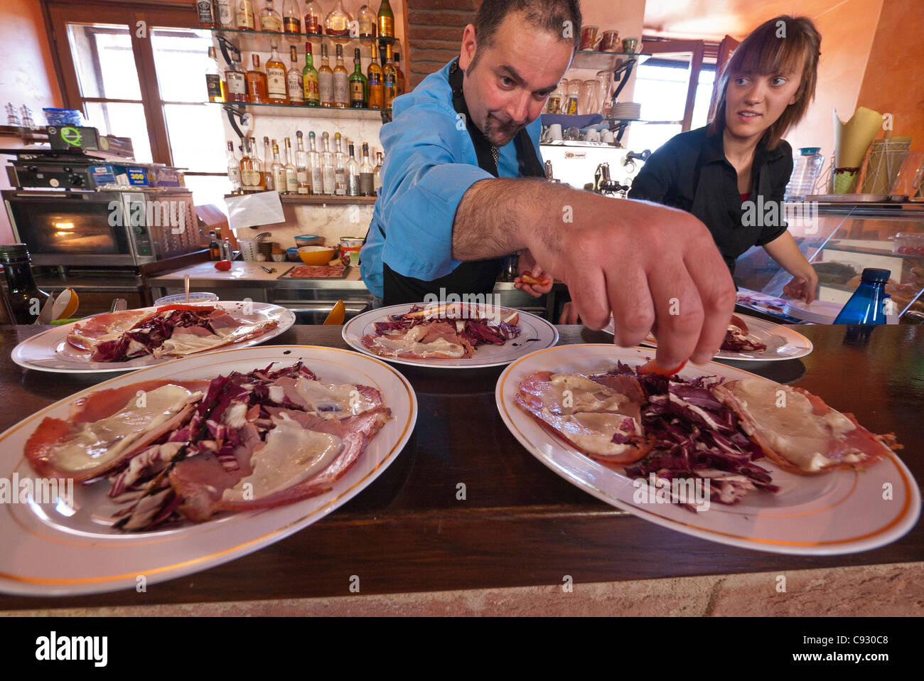 A restaurant owner and the waitress prepare plates of food for serving ...