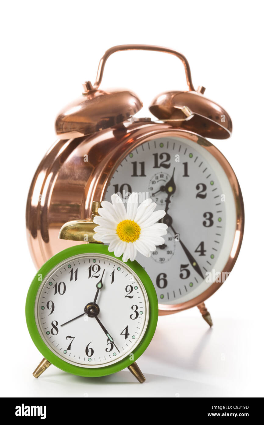 Two alarm clocks with daisy flower on white Stock Photo - Alamy