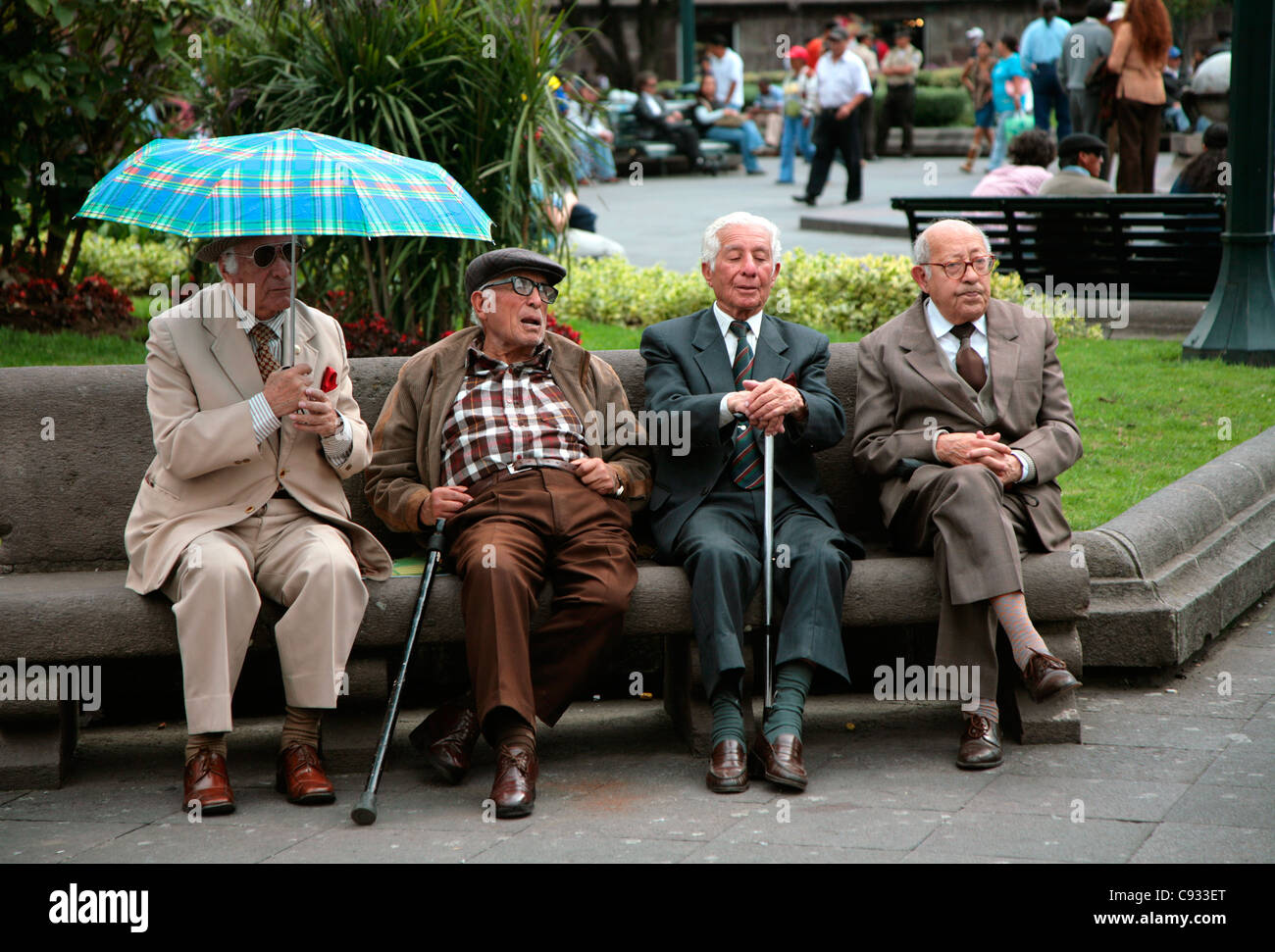 Ecuador, Quito. Four old men discuss events in a park in the Plaza de ...
