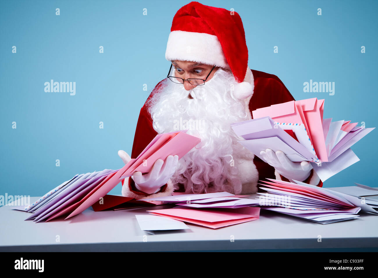 Portrait of confused Santa Claus holding letters and looking at them in ...