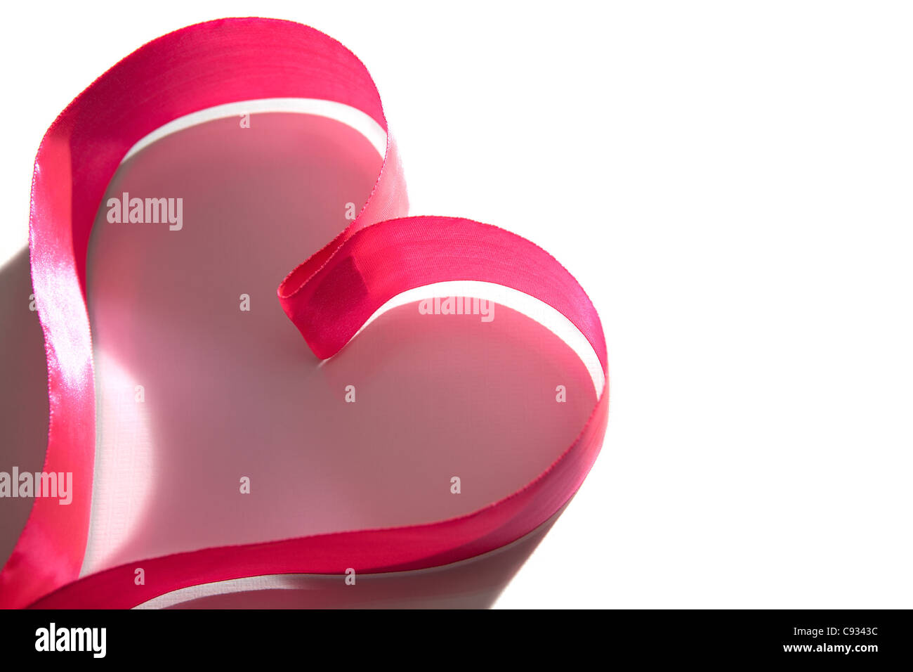 Form of heart made up of pink ribbon over white background Stock Photo ...