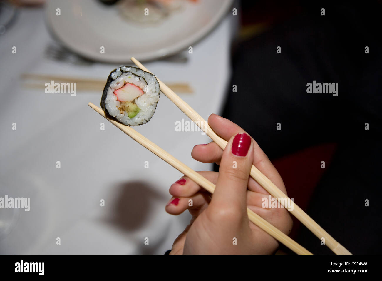 Sushi on chopsticks Stock Photo - Alamy