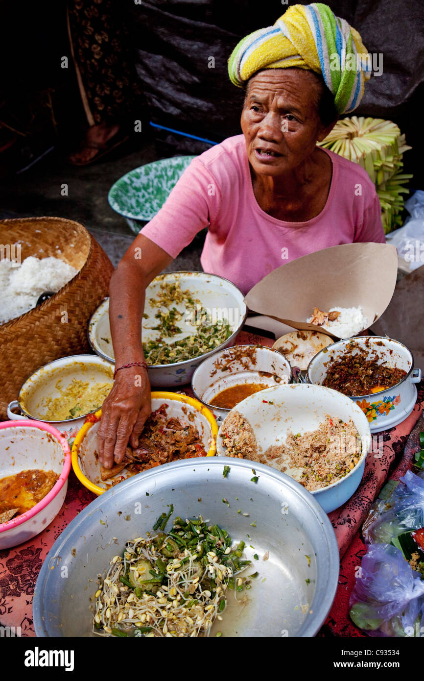 Bali, Ubud. A lady serves up traditional Balinese food for breakfast at ...