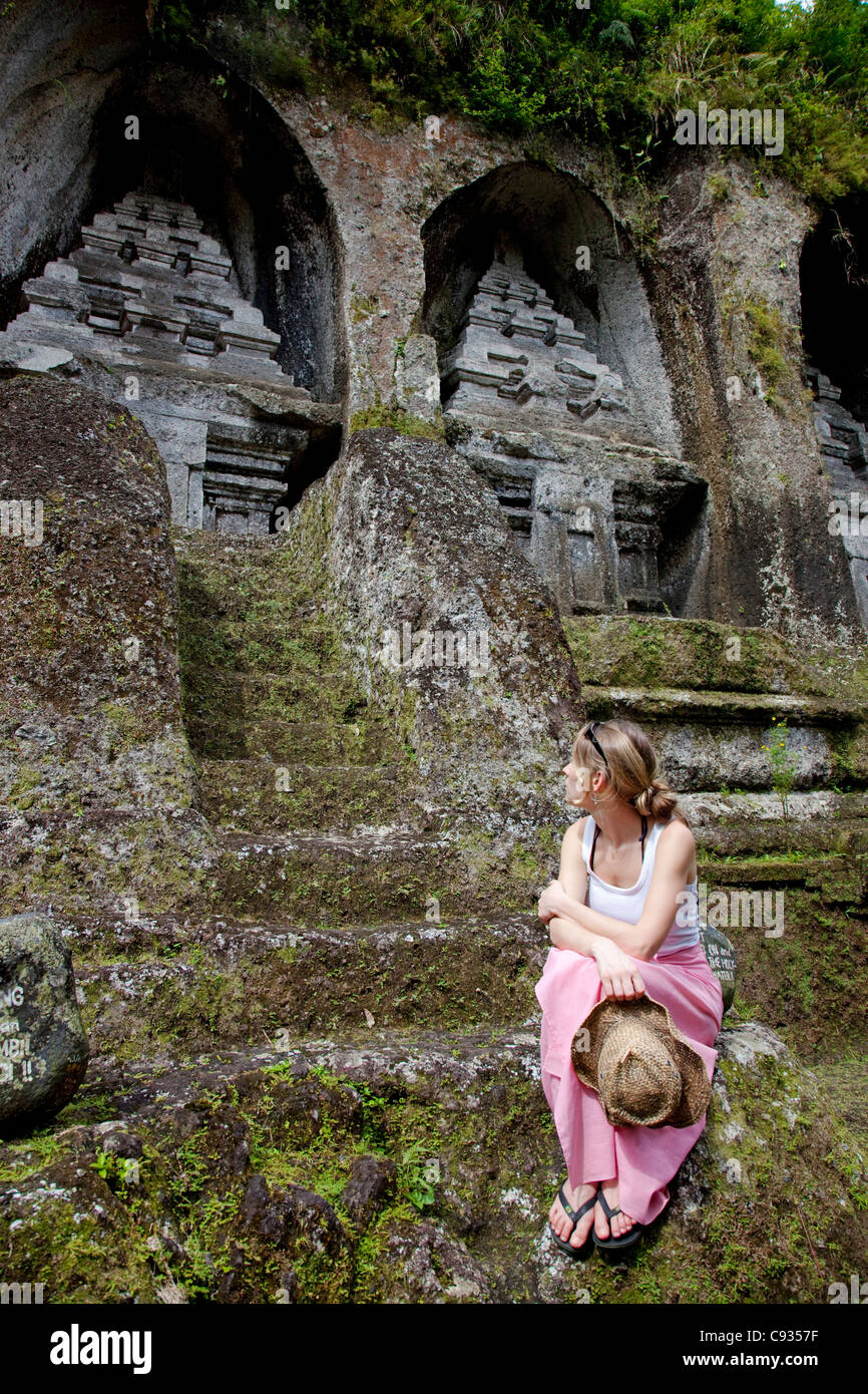 Bali, Ubud. A tourist gazes at the huge shrines carved out of the cliff ...