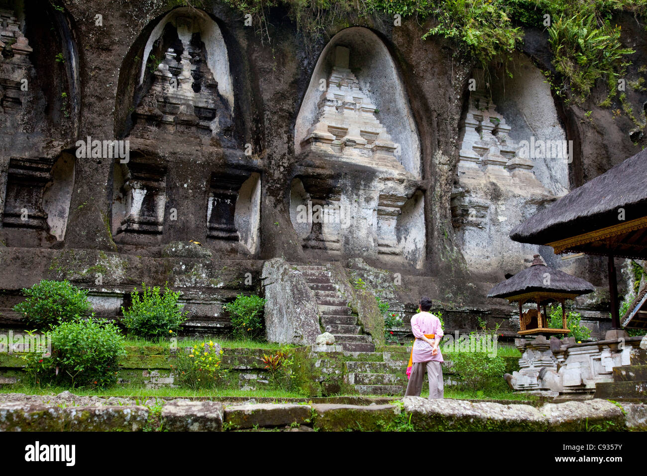 Bali, Ubud. A tourist gazes at the huge shrines carved out of the cliff ...