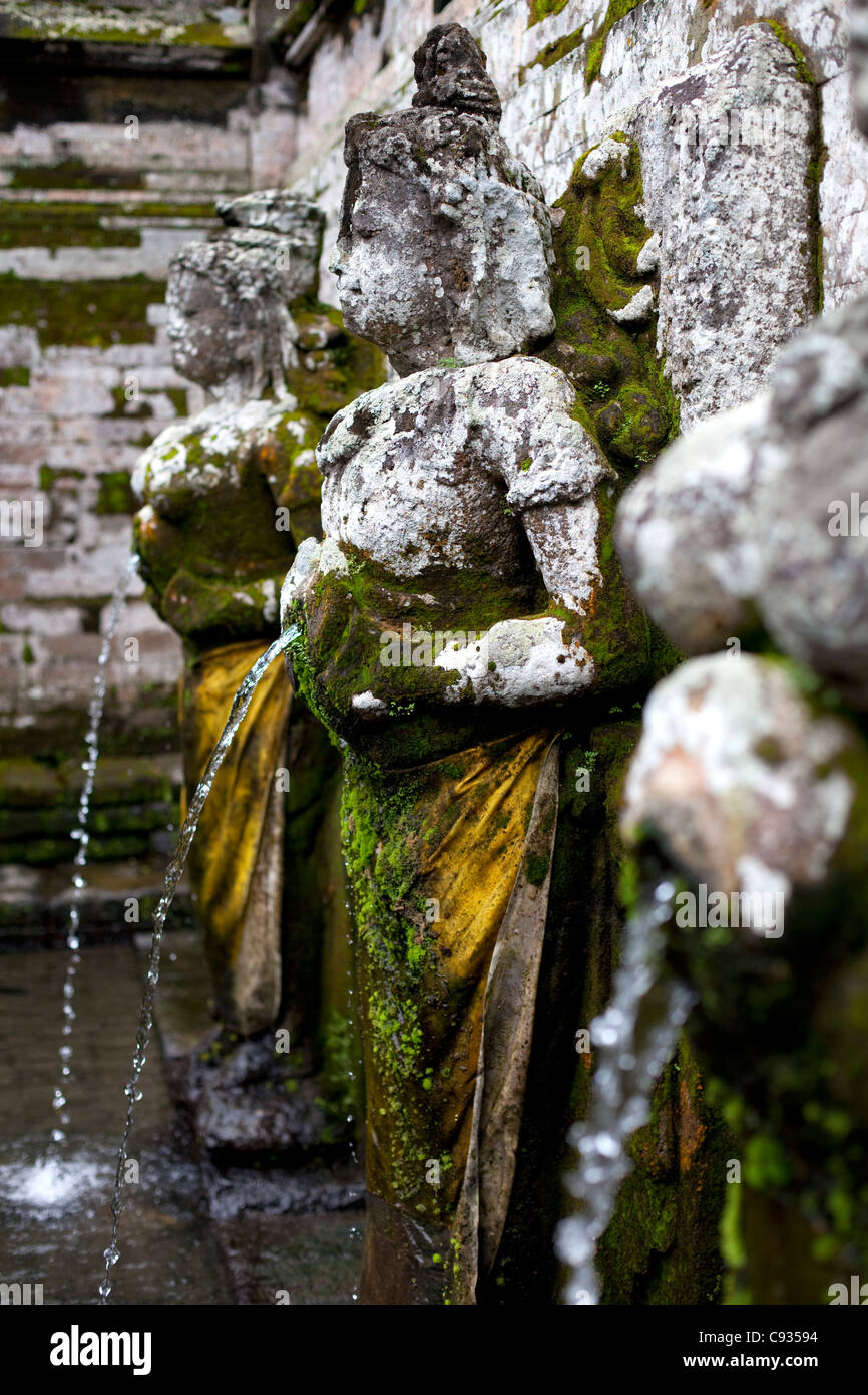 Bali, Ubud. Ancient granite statues pour water into the bathing pool of ...