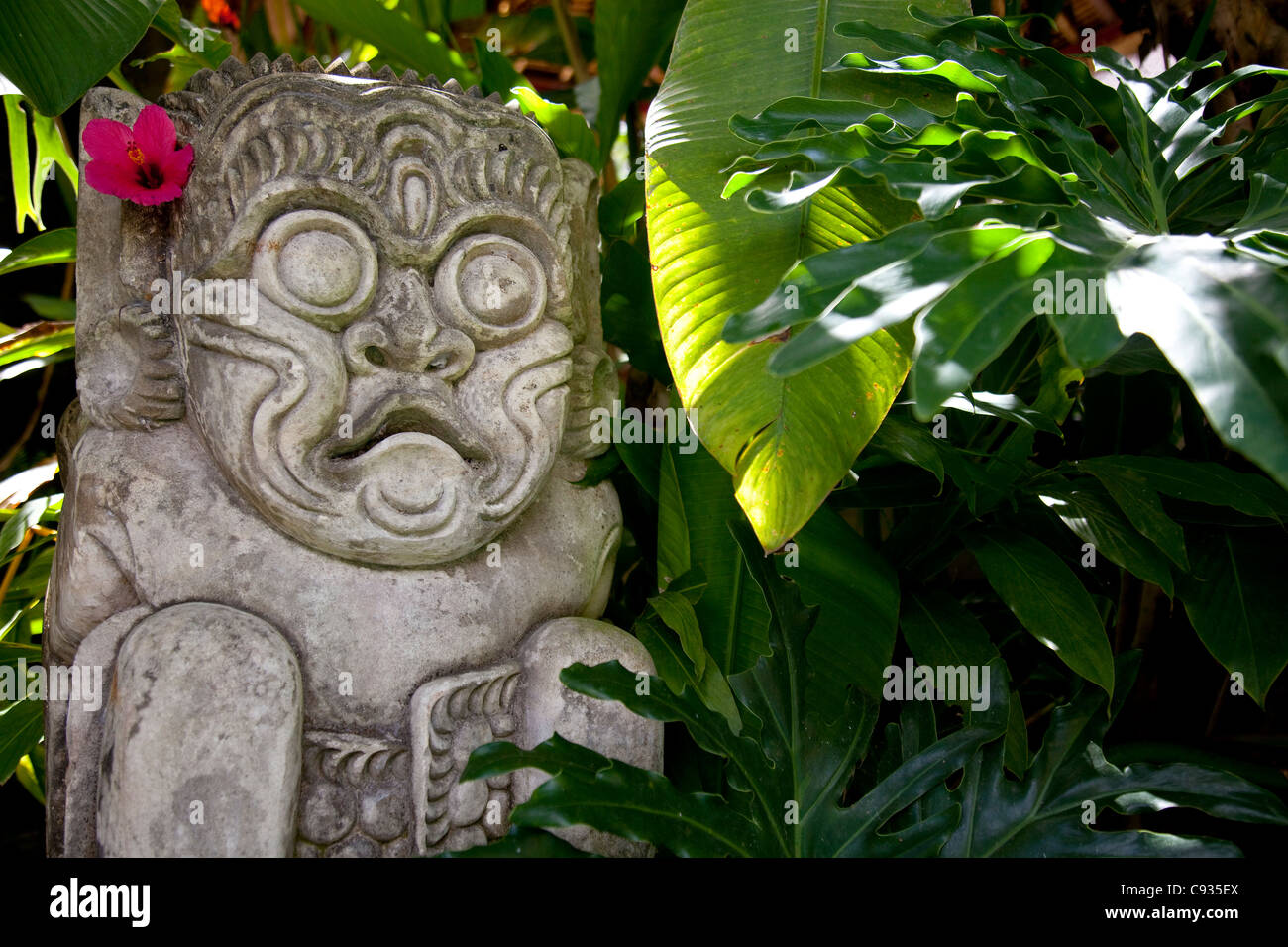 Bali, Ubud. A stone carving, adorned with a hibiscus flower, sits in ...