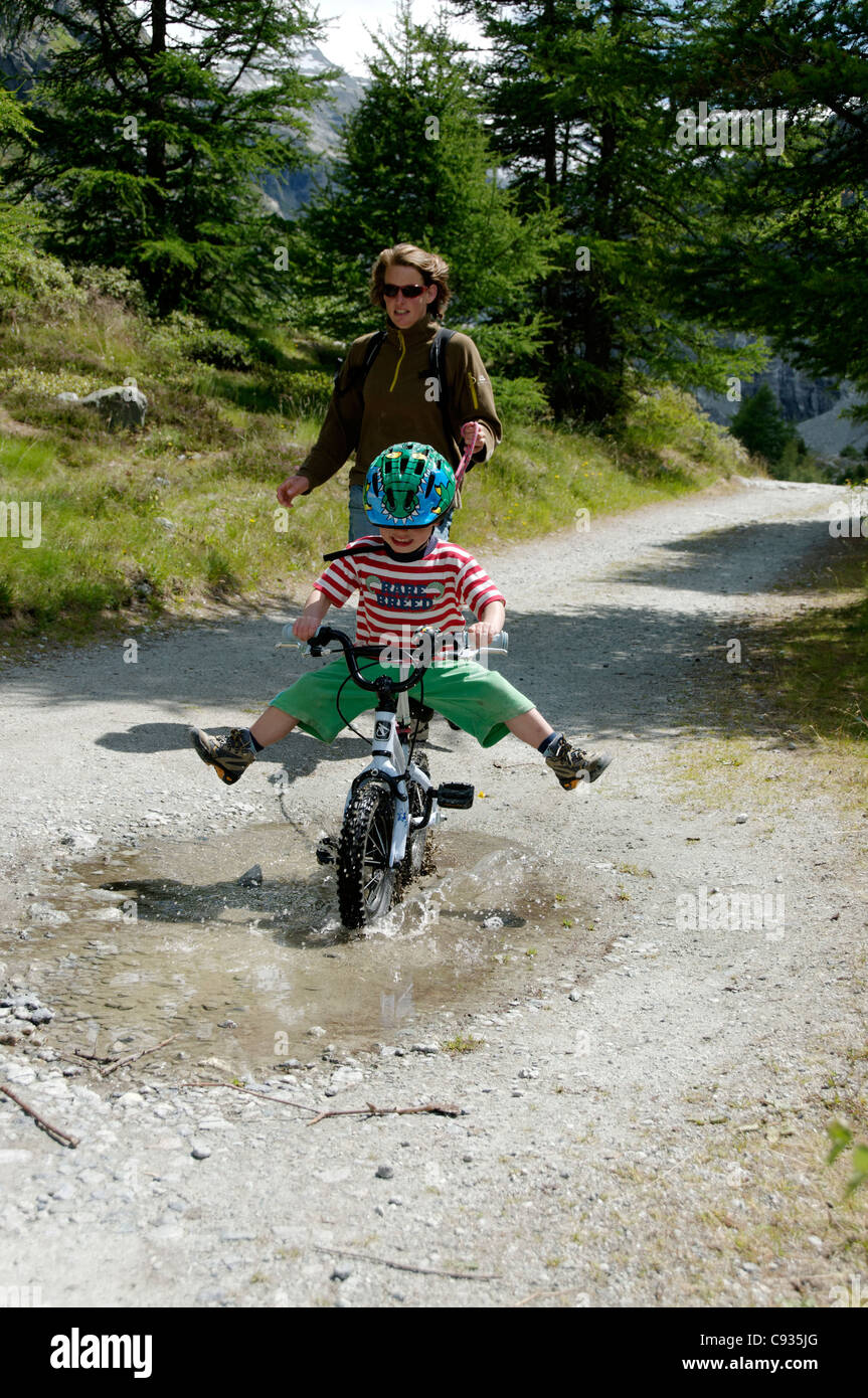 A boy riding a bike through a puddle Stock Photo - Alamy