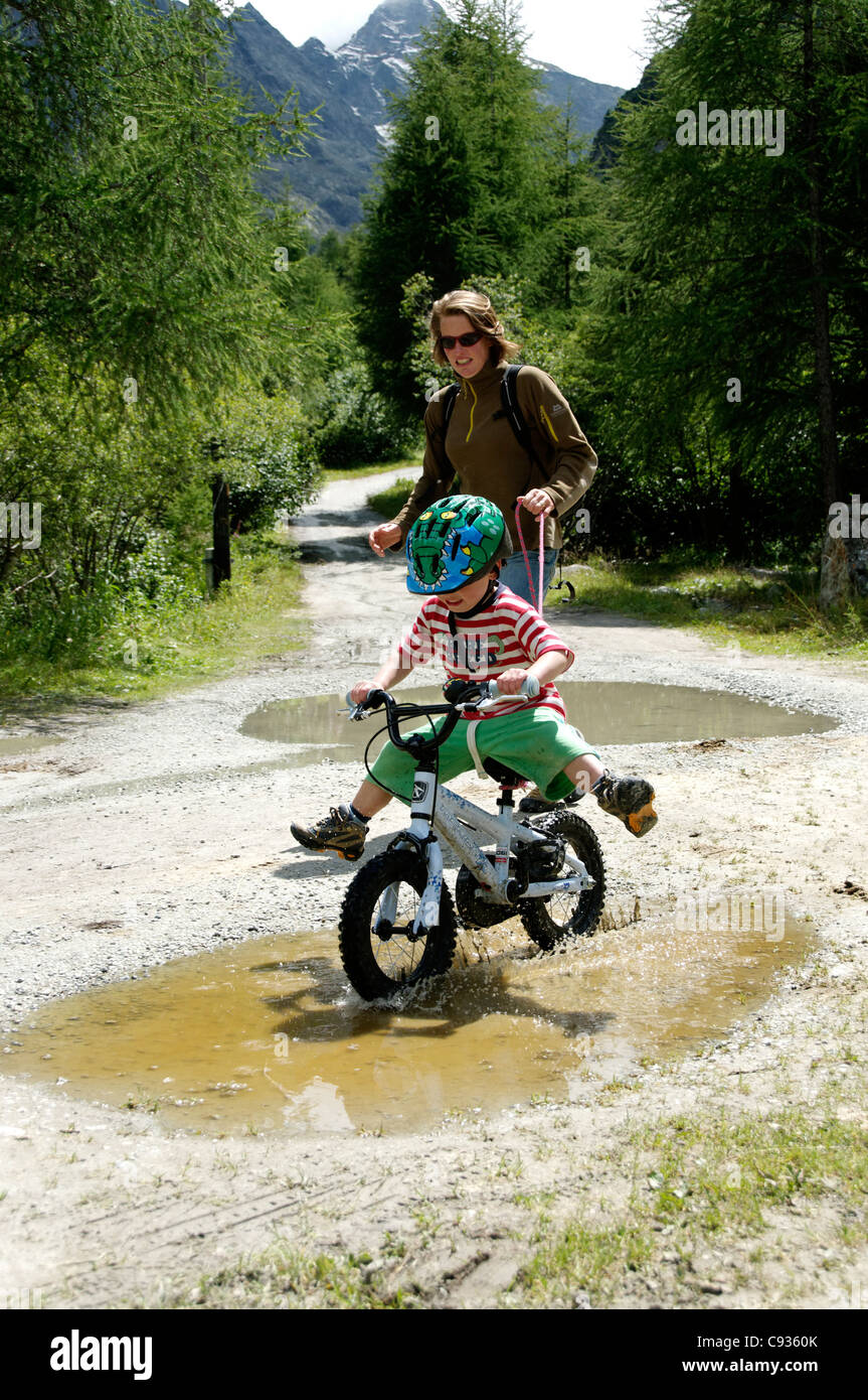 A boy riding a bike through a puddle Stock Photo - Alamy
