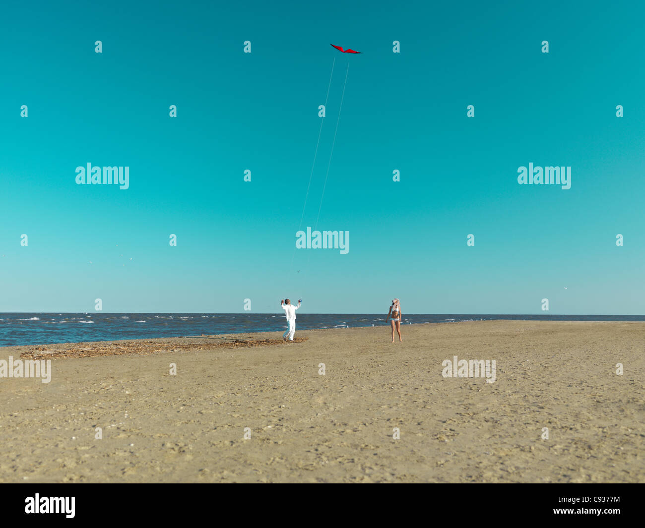 happy, active, young couple flying a red kite on the seashore Stock ...