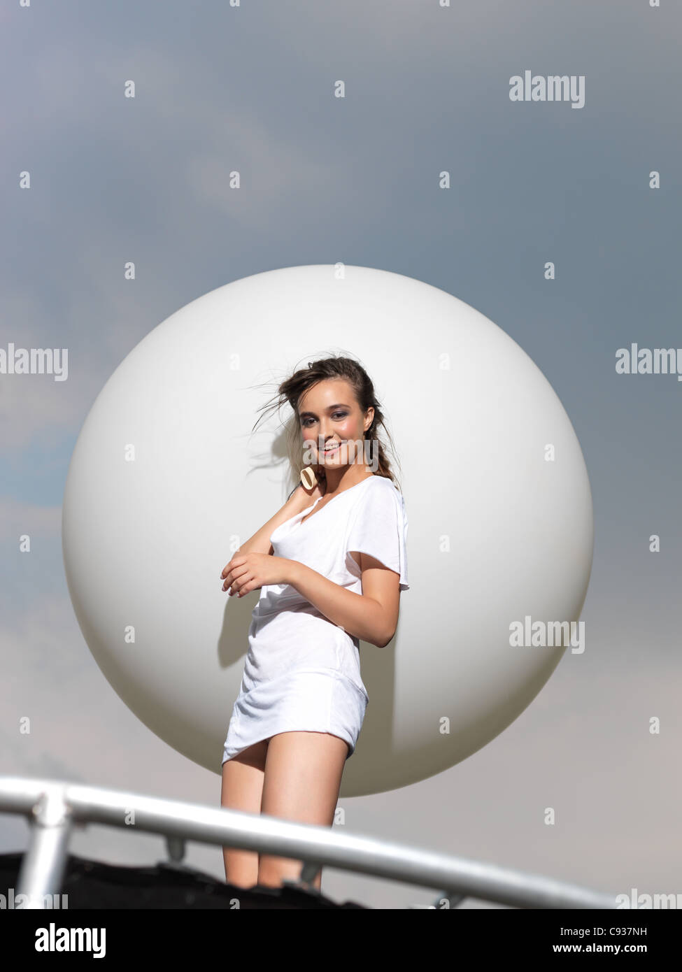 happy, young woman standing on a trampoline, holding a big, white ...